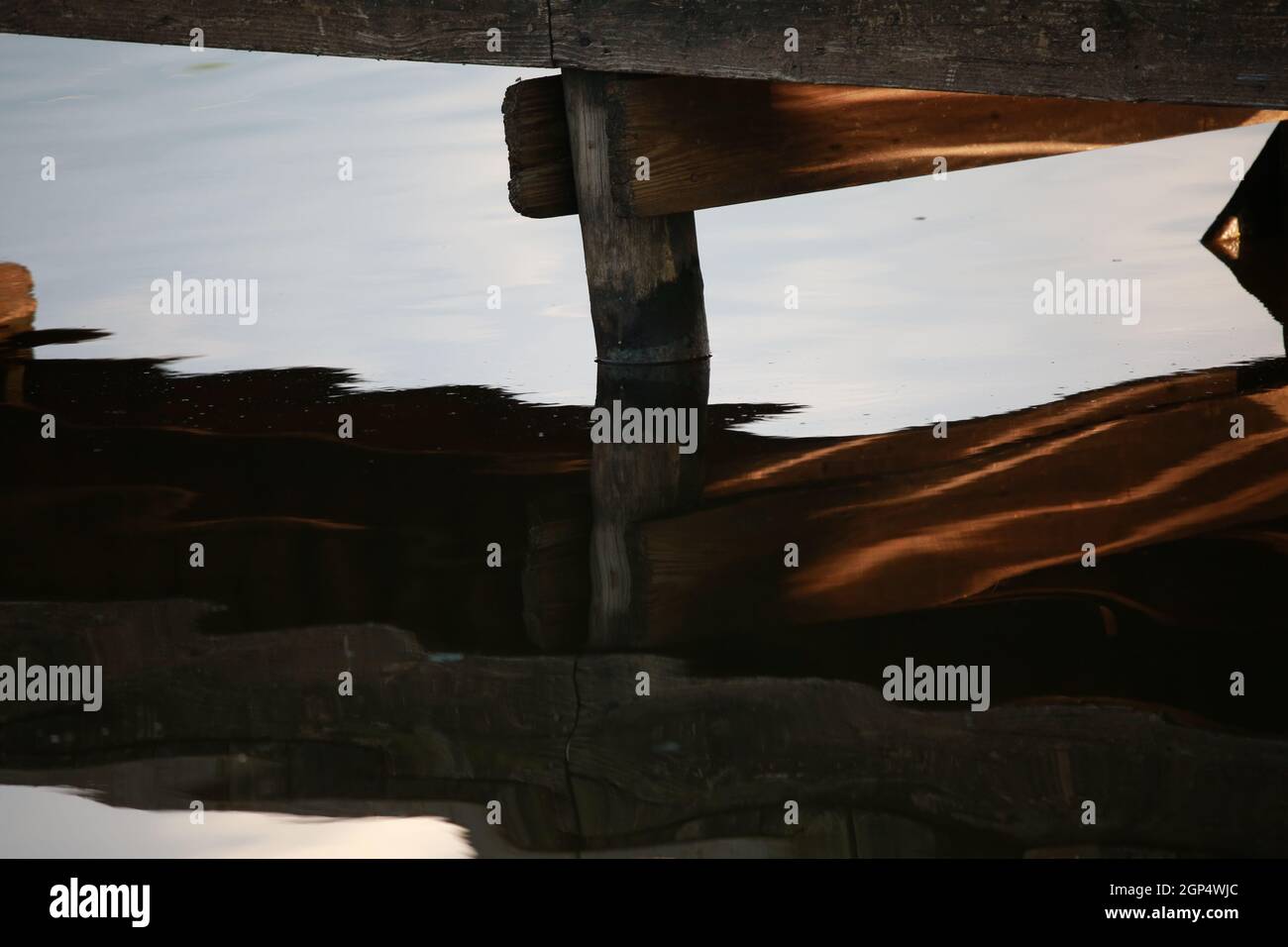 Wooden pier and its reflection in the water below Stock Photo - Alamy