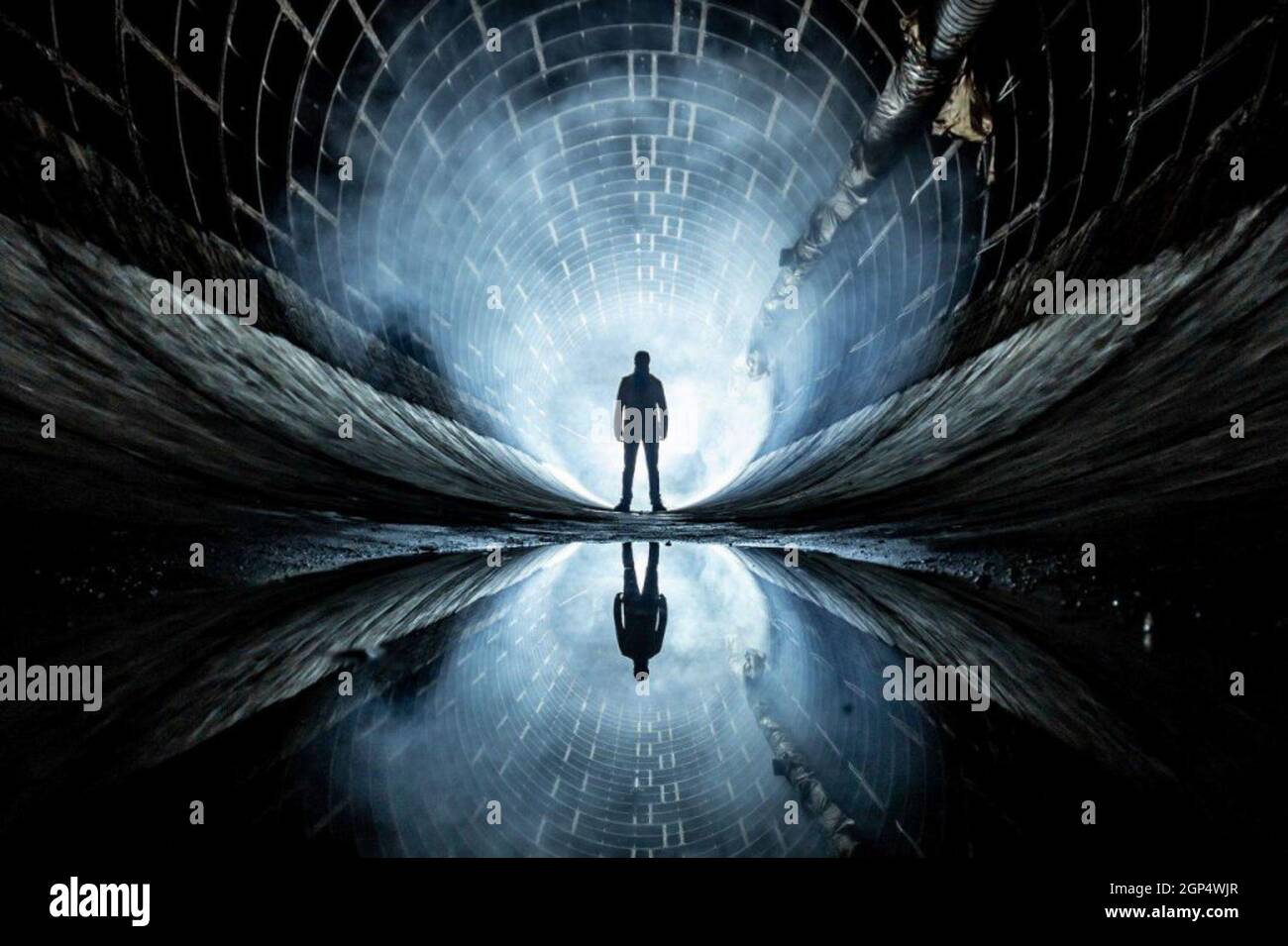 A man stands in a tunnel against the light at the end of the tunnel ...