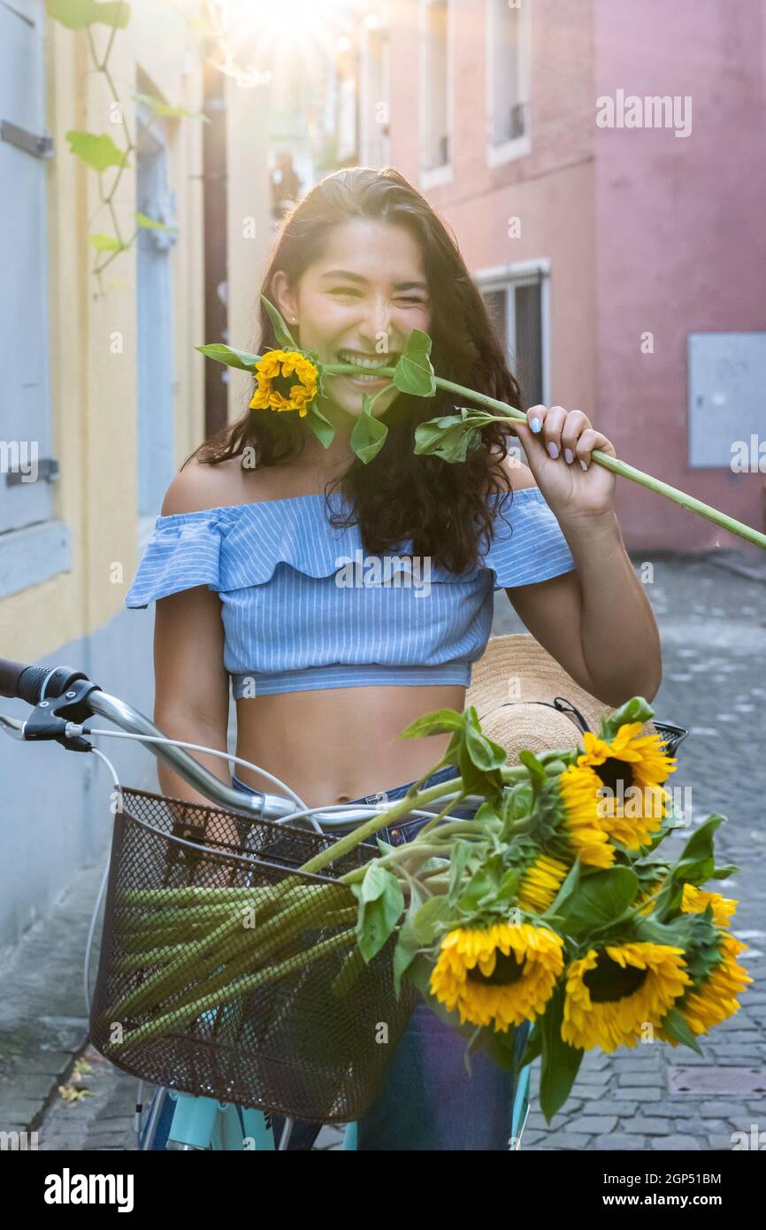 Beautiful young lady biting in sunflower while walking through the old ...