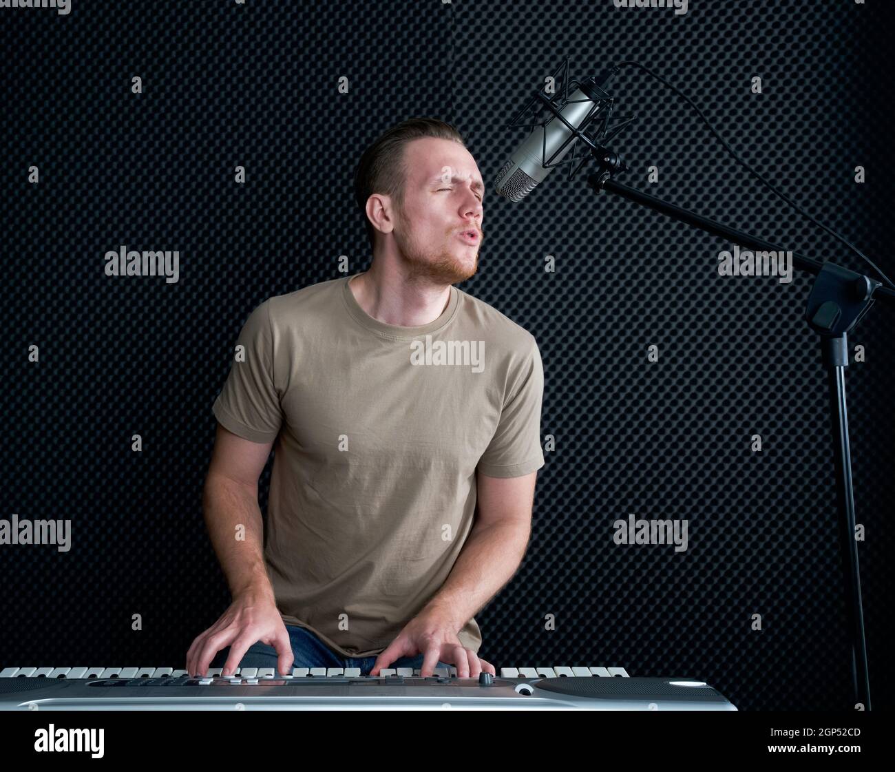 Young caucasian man sings while playing an electric keyboard in front ...