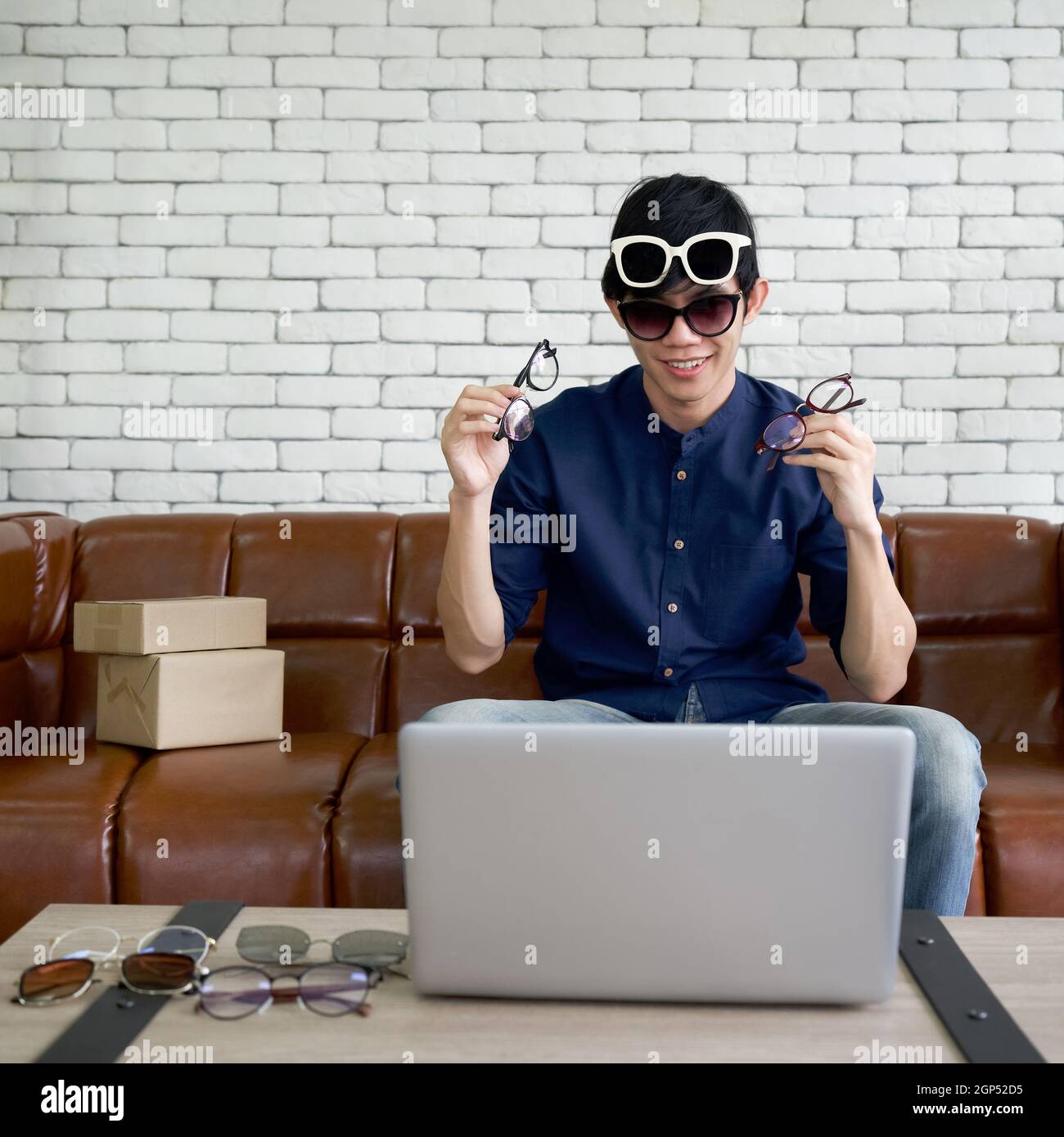 Young man wearing two sunglasses and holding two more glasses facing to ...