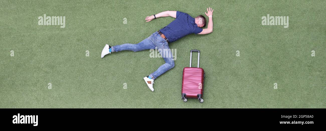 Motionless man lies on green lawn with suitcase Stock Photo - Alamy