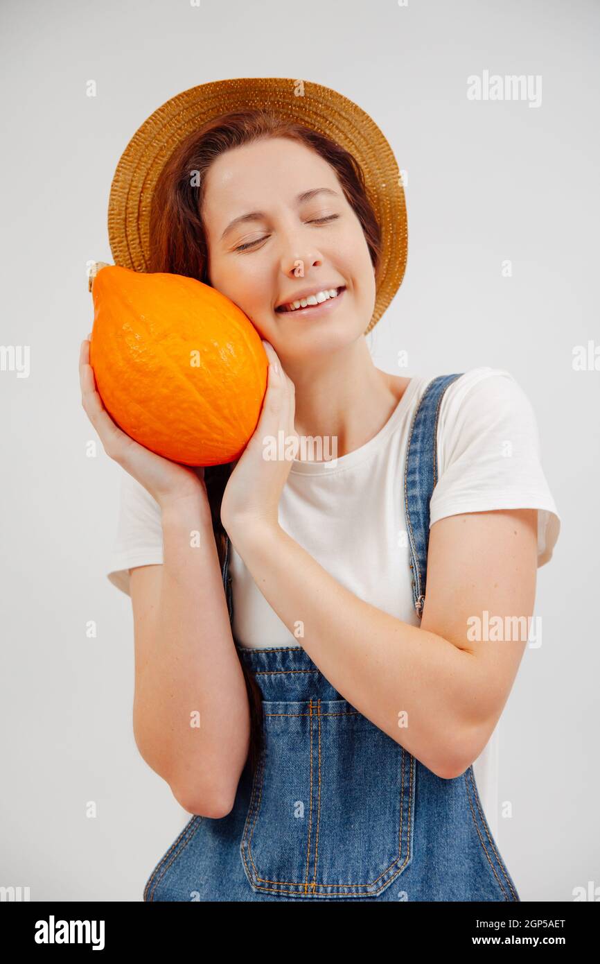 Female agricultural farmer smiles while clutching small ripe pumpkin ...