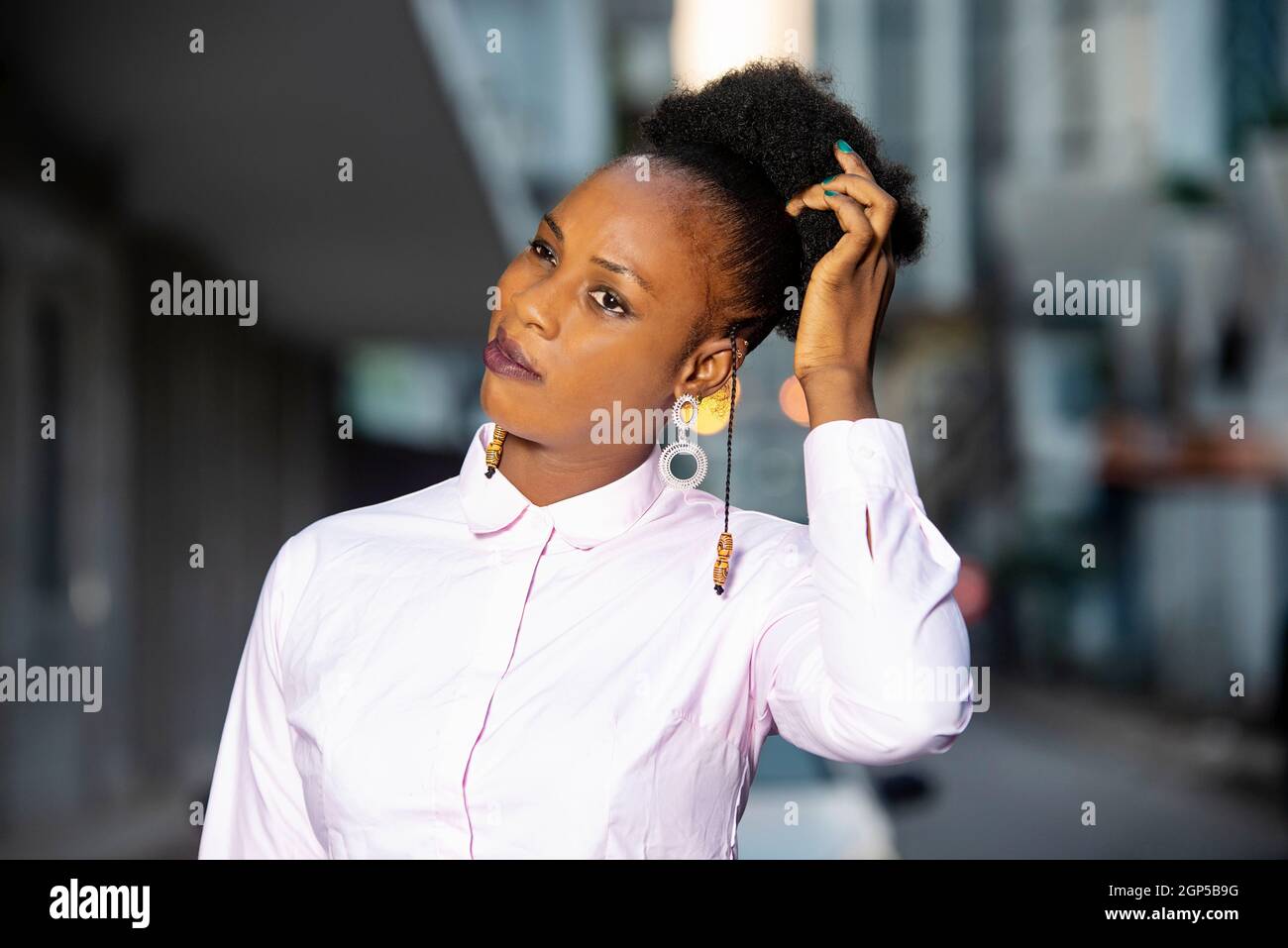 charming young african woman standing outdoors scraping her hair Stock ...