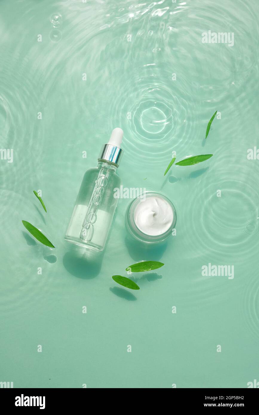 Set of moisturizing cosmetic products on water with drops. Glass bottle ...