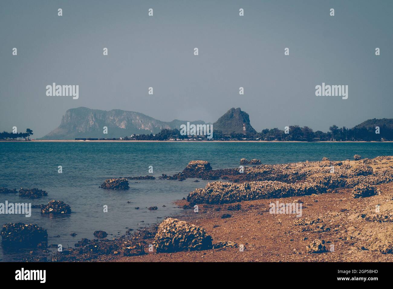 Beach, rocks, mountains. Dramatic gold and blue coastline. Sharp rough ...