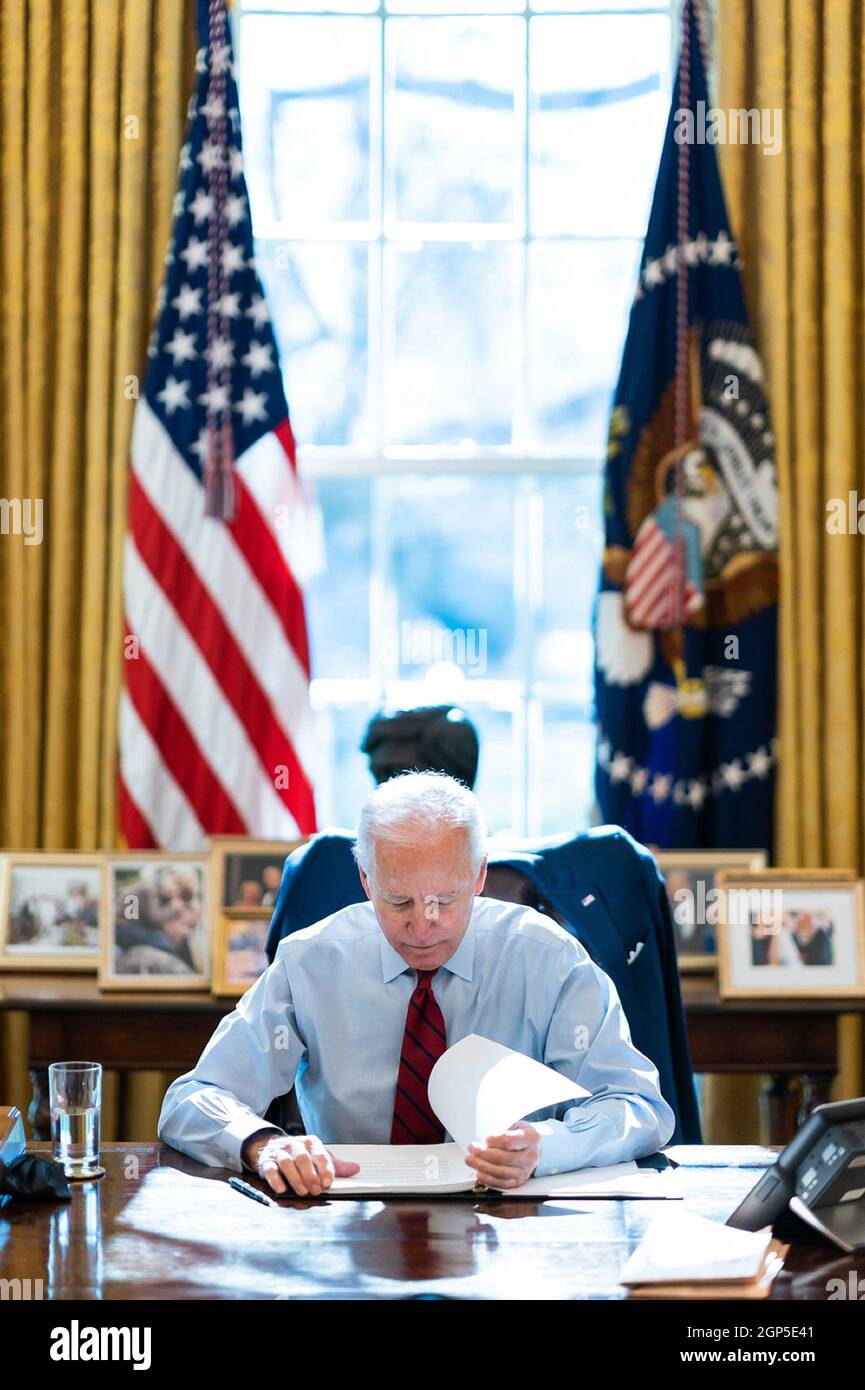 President Joe Biden reading documents at his desk in the White House ...