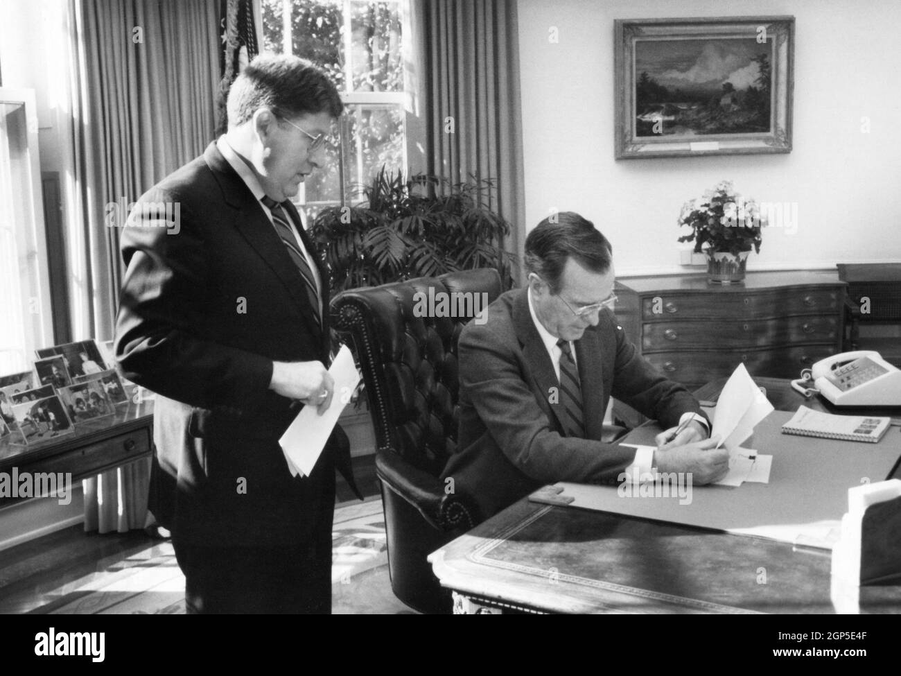 President George H.W. Bush, at his desk in the Oval Office, speaks to ...