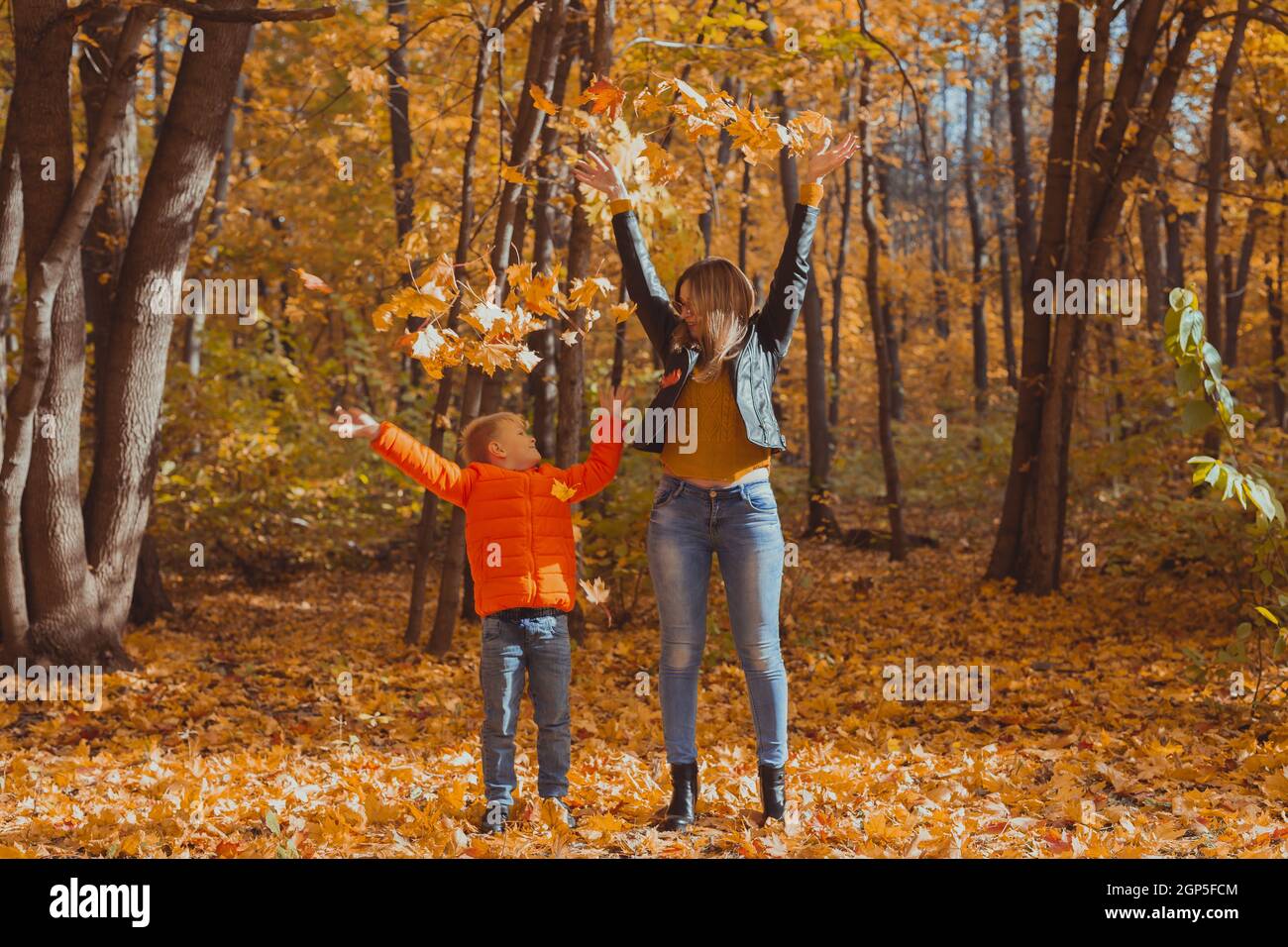 Single parent family playing with autumn leaves in park. Happy mom and ...