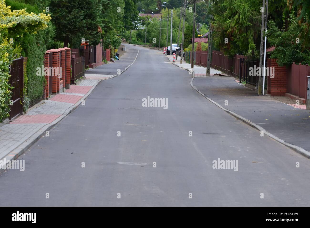 Asphalt road between houses with fences and gardens. Summer Stock Photo ...