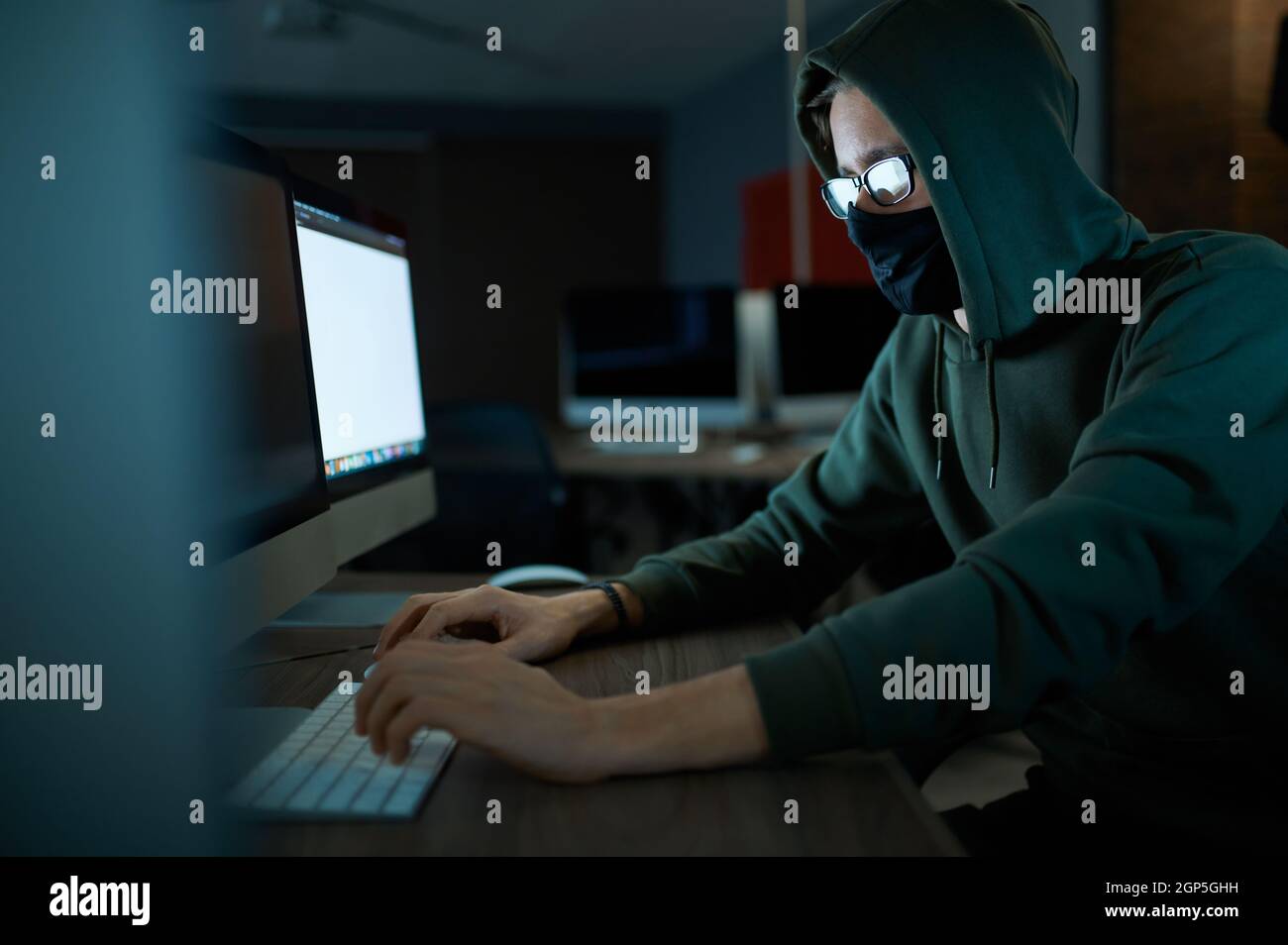 Male Internet Hacker In Hood Holds Laptop Front View Illegal Web Programmer At Workplace