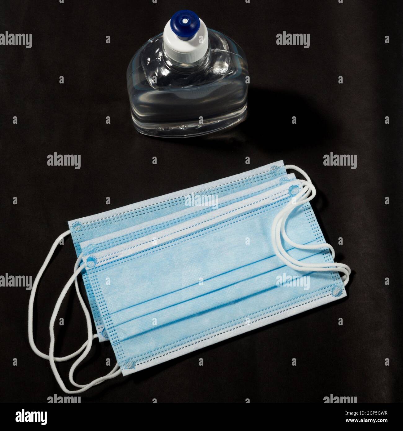 Alcohol gel hand sanitizer and disposable hygienic mask on black ...