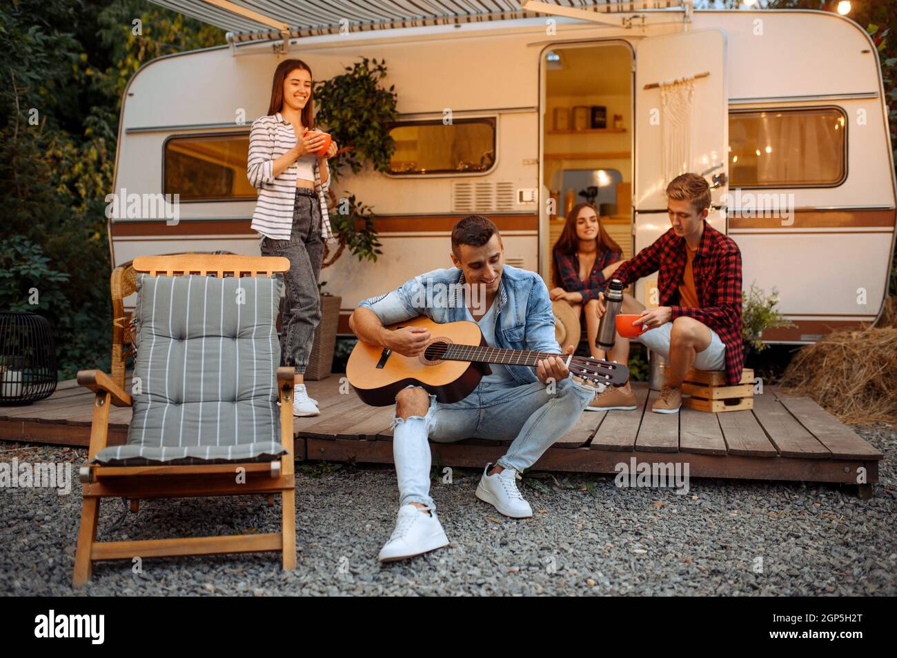 Happy friends sing songs with guitar on picnic at camping in the forest ...