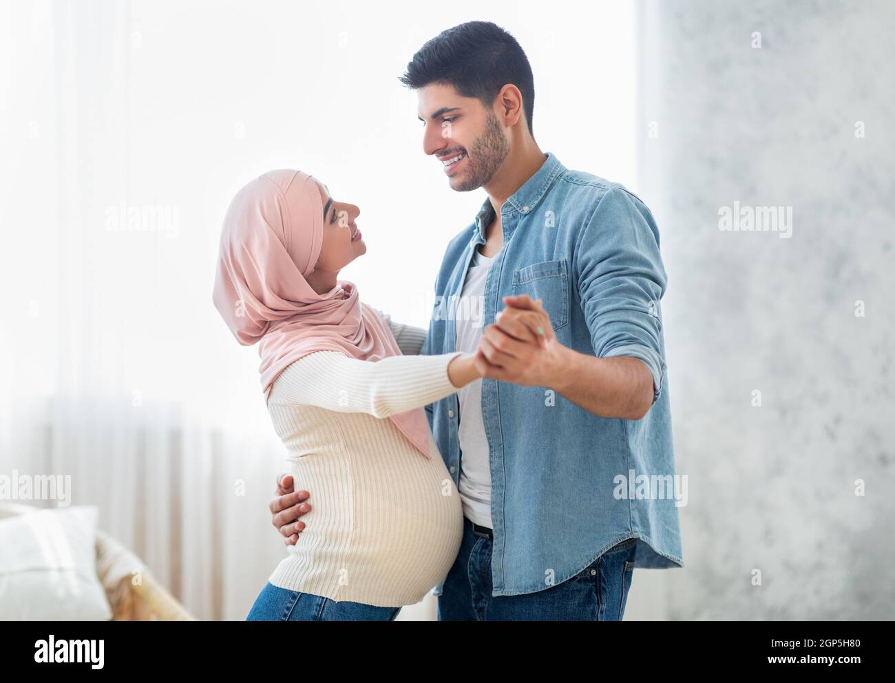 Romantic arab pregnant couple dancing waltz at home in living room ...
