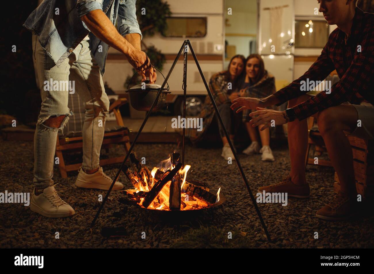 Friends warming themselves by the campfire, picnic at camping in the ...