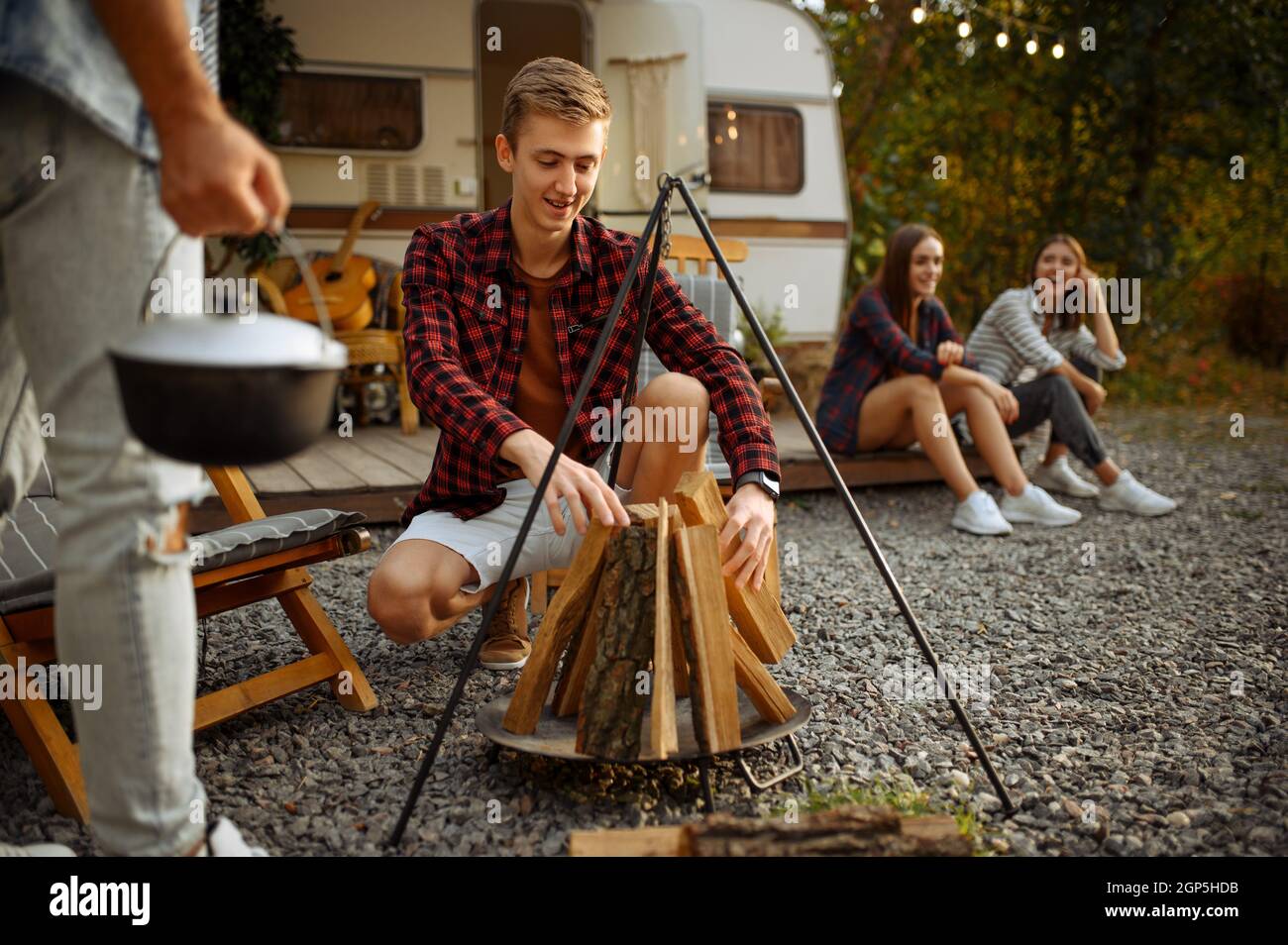 Happy friends prepares to cooking on campfire, picnic at camping in the ...