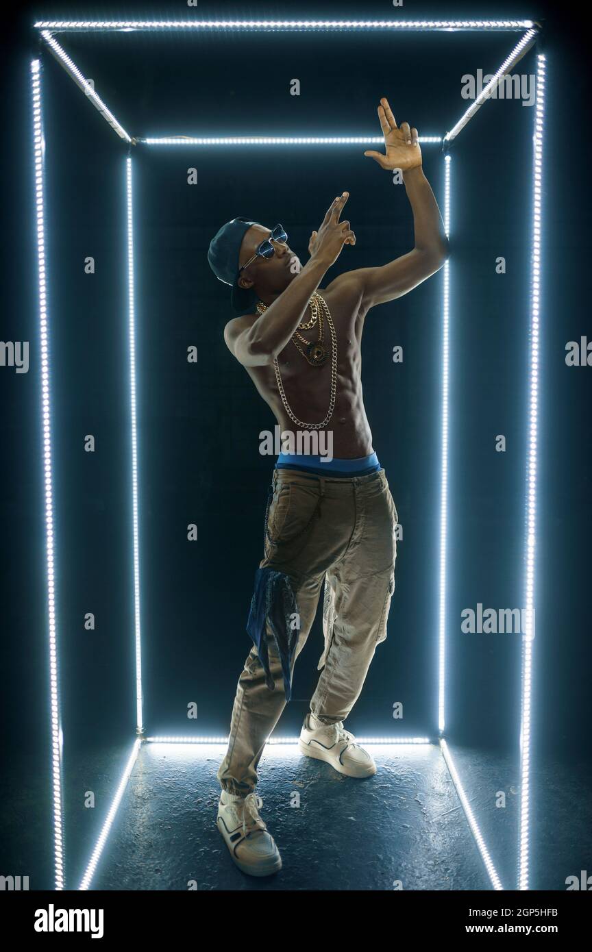 Serious rapper in gold chains, bottom view, dark background. Hip-hop ...