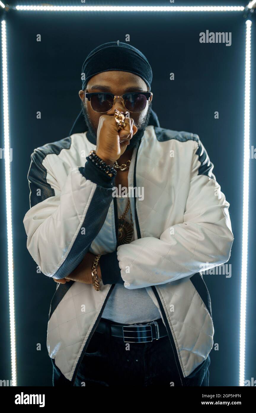 Stylish rapper in sunglasses, dark background. Hip-hop performer, rap ...