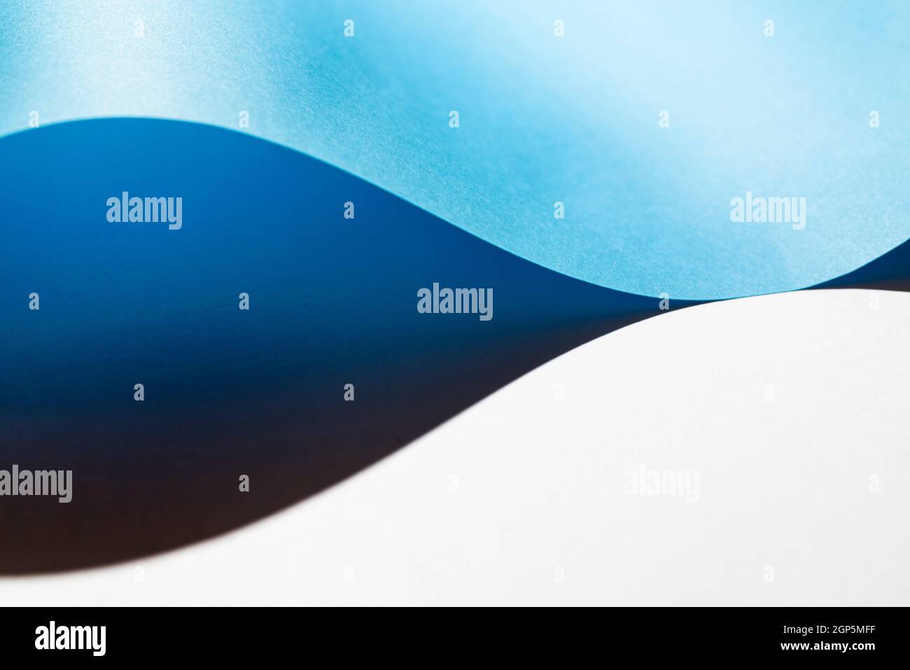 the shadow formed by a sheet of light blue paper folded on the white ...