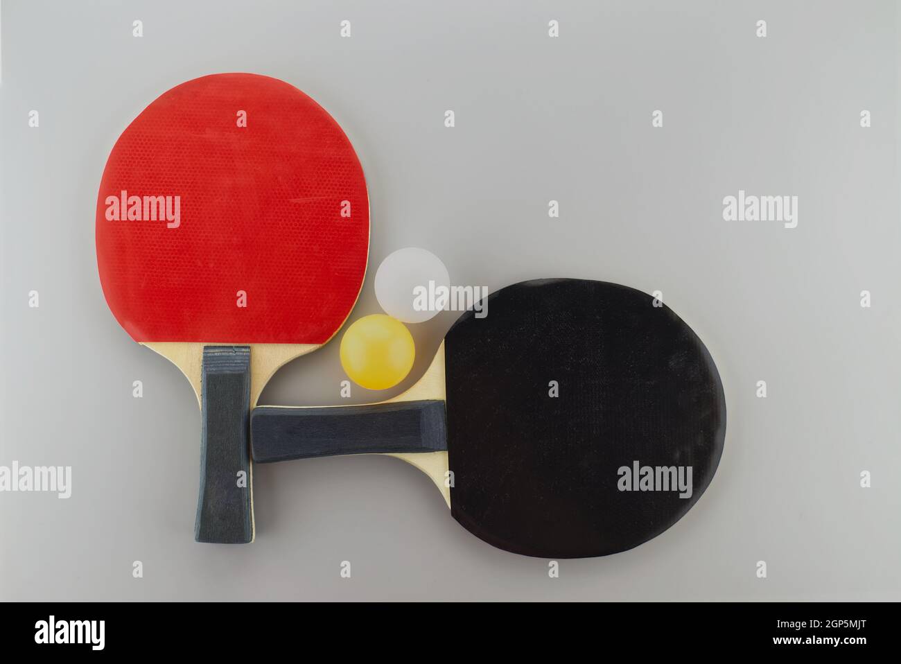 Two table tennis racks with a white and yellow ping pong ball on grey ...