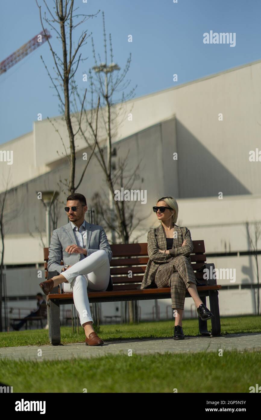 Two business people are sitting on the bench while thinking about the ...