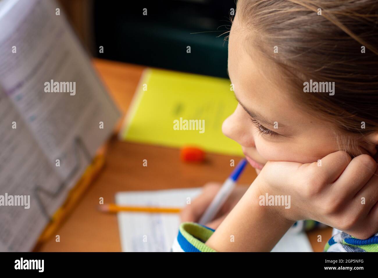 Close-up of a girl doing homework, a girl lost in thought distracted ...