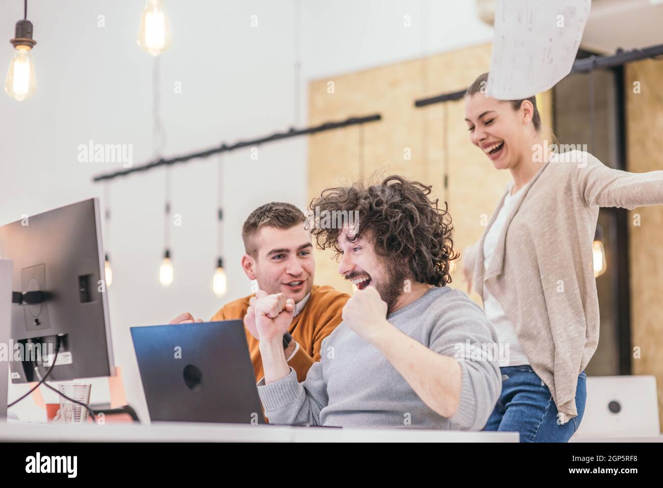 Happy surprise for the teammates. Coworkers cheering while looking at a ...