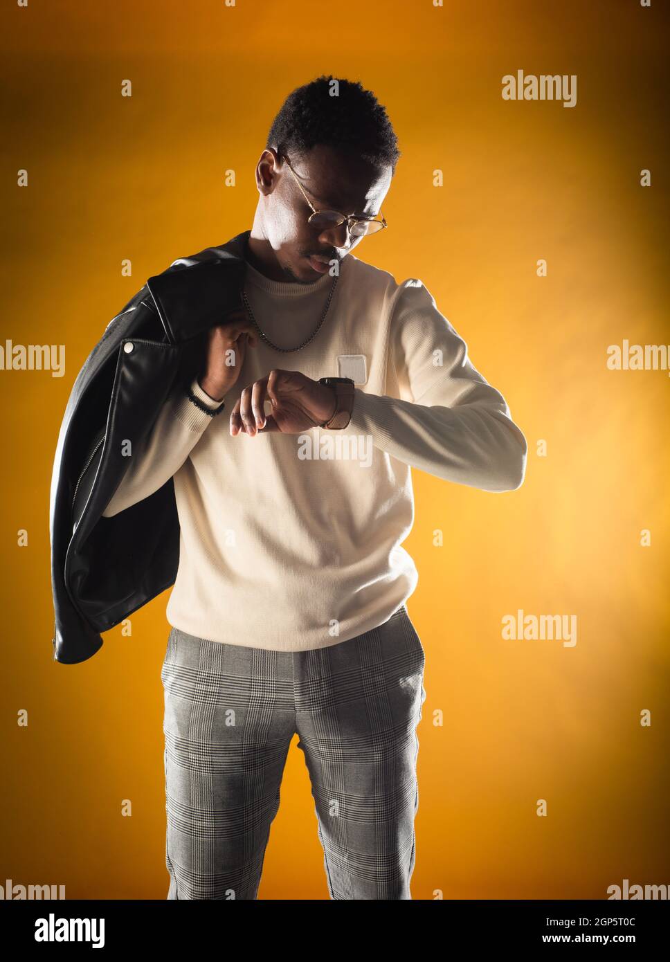 Young black male is posing on yellew background while looking at the ...