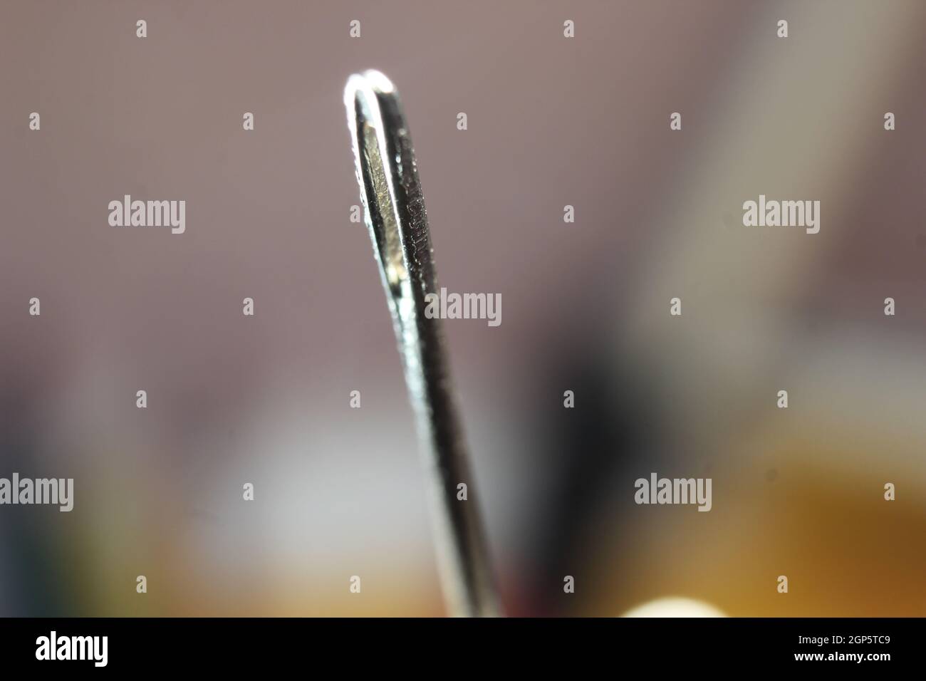 Macro photograph of sewing needle. Small needle with empty eyelet ...
