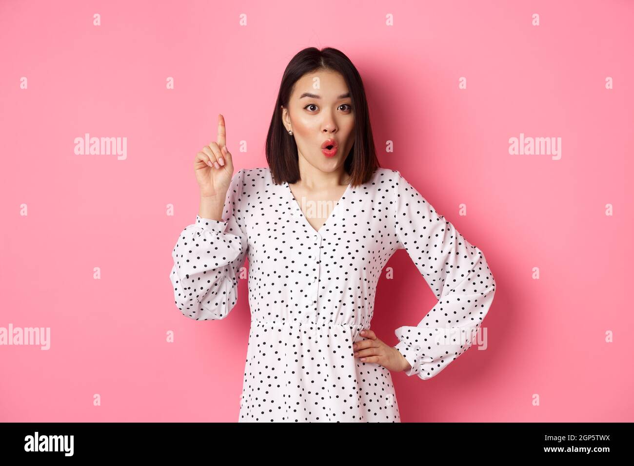 Excited asian girl having an idea, saying suggestion, raising finger ...