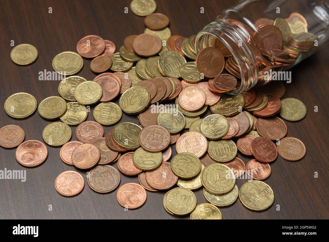 Coins spilling from a glass jar Stock Photo - Alamy
