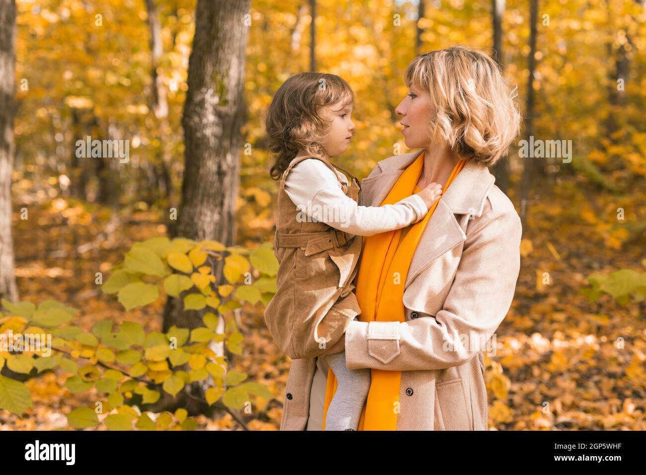 Young mother with her little daughter in an autumn park. Fall season ...