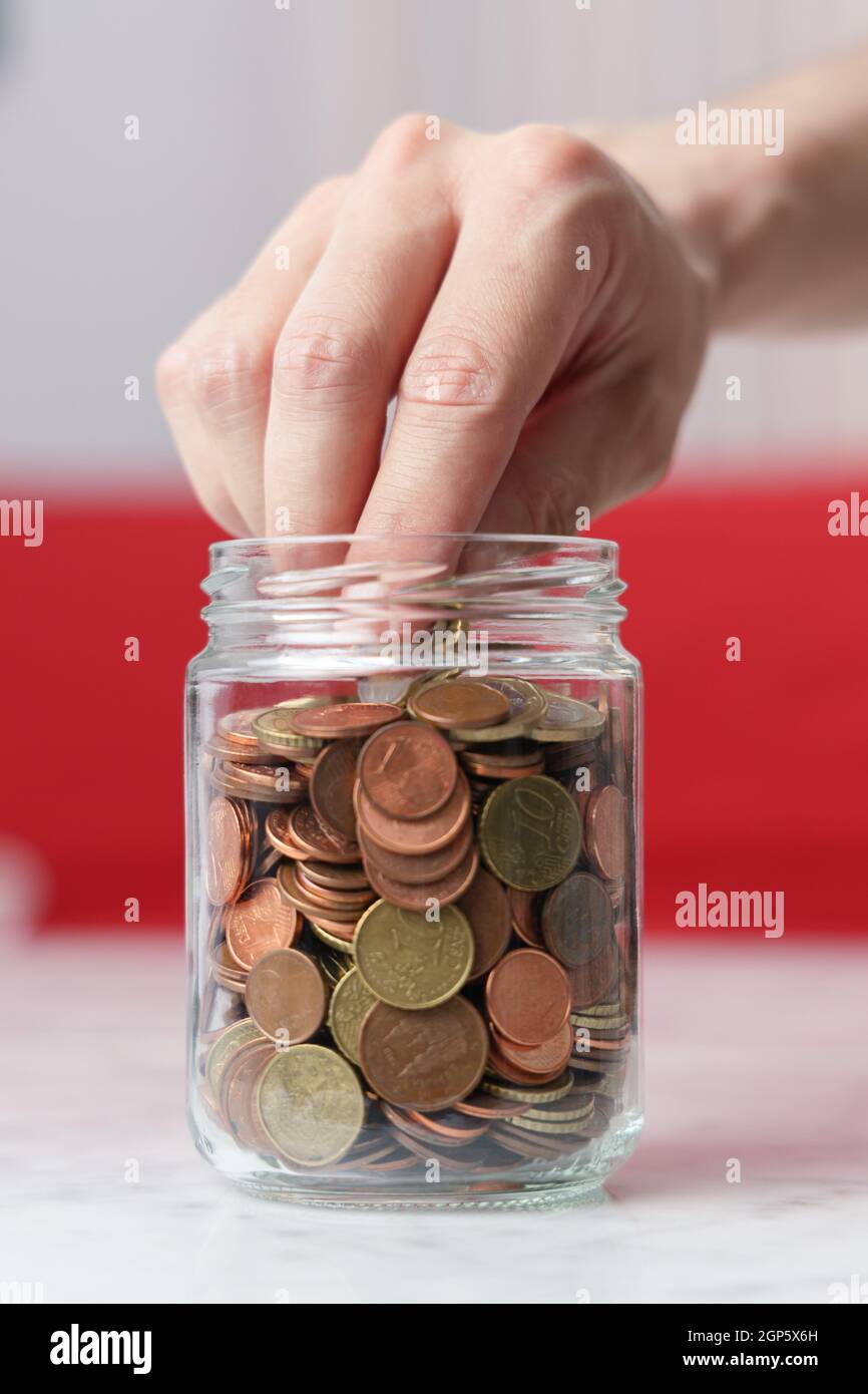 Hand picking up a coin from a glass jar Stock Photo - Alamy
