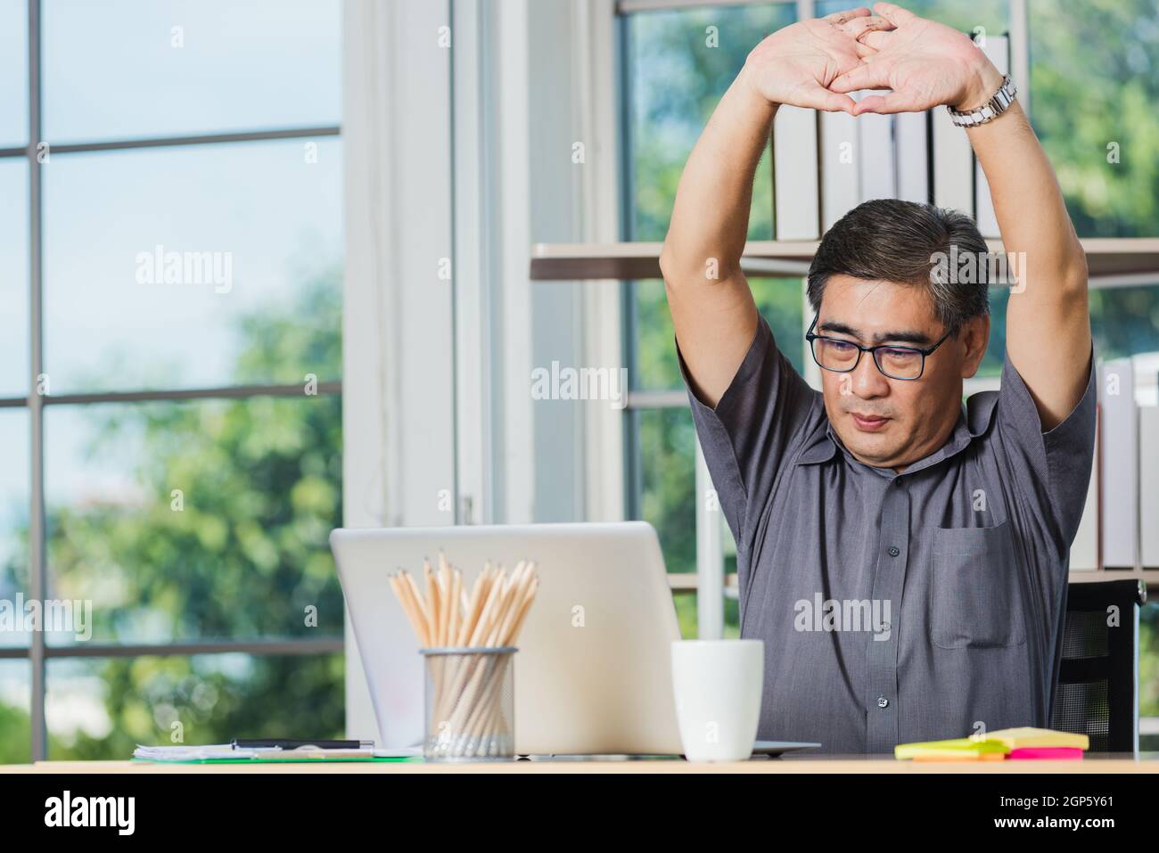 Asian businessman tired overworked he stretch oneself on the desk ...