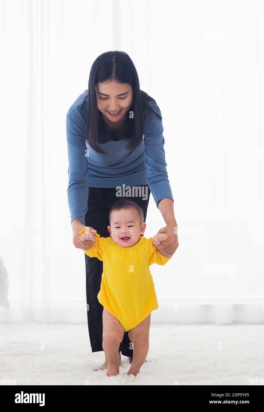 Asian little baby girl taking first steps learning to walk with mom ...