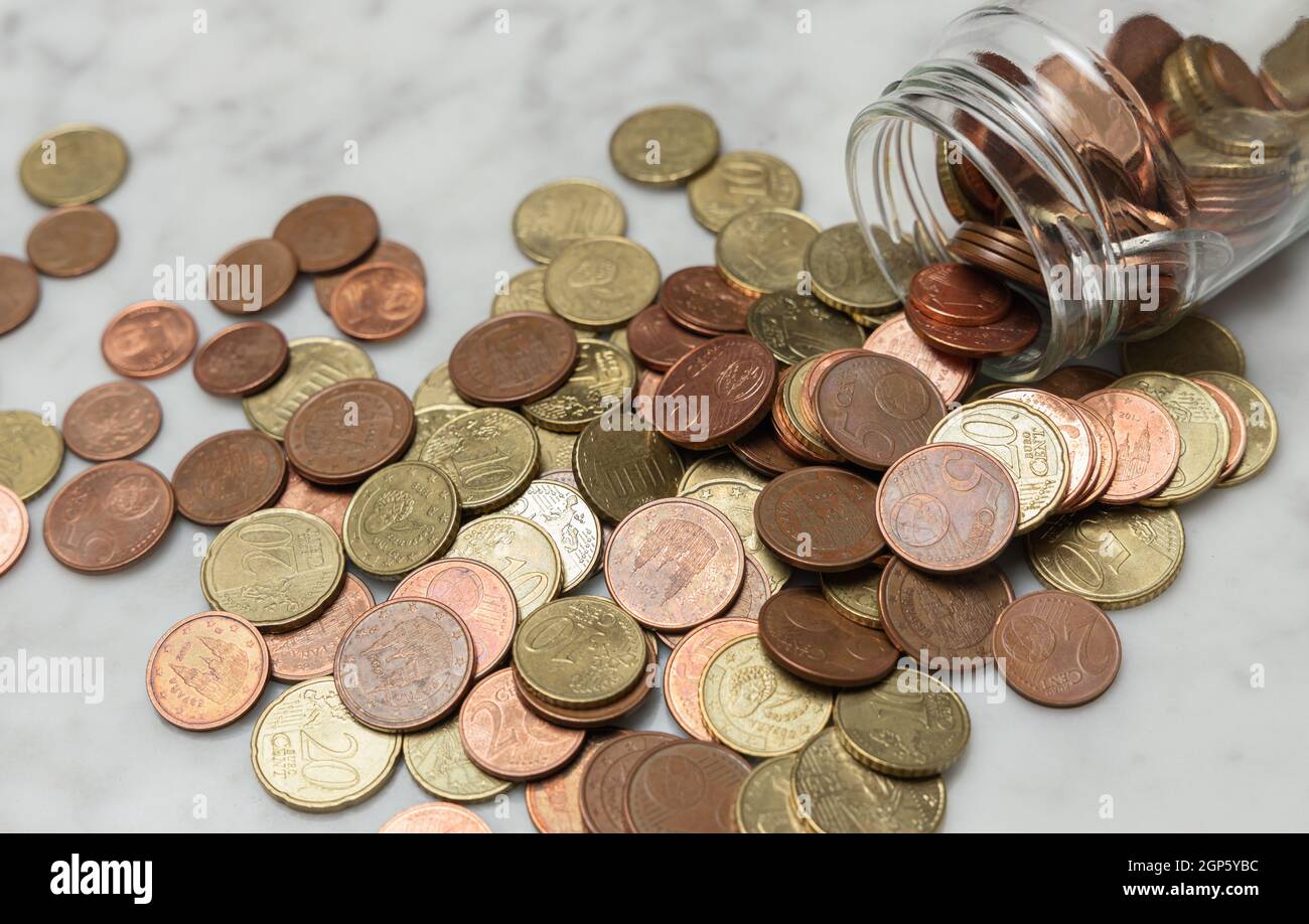 Coins spilling from a glass jar Stock Photo - Alamy