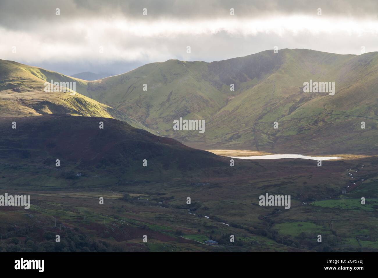 Sun rays shining on Llyn Dwythwch, a mountain lake. Llanberis, Gwynedd ...