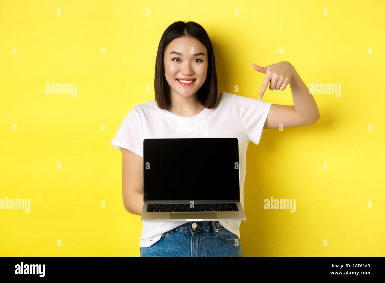 Young asian woman demonstrate online offer, showing laptop screen and ...