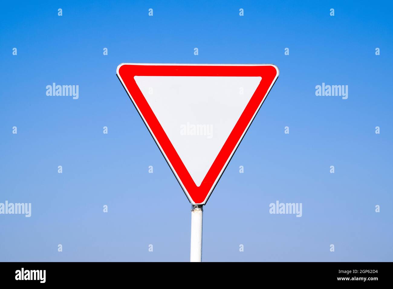 Road signs, give way. Sign on a blue background Stock Photo - Alamy