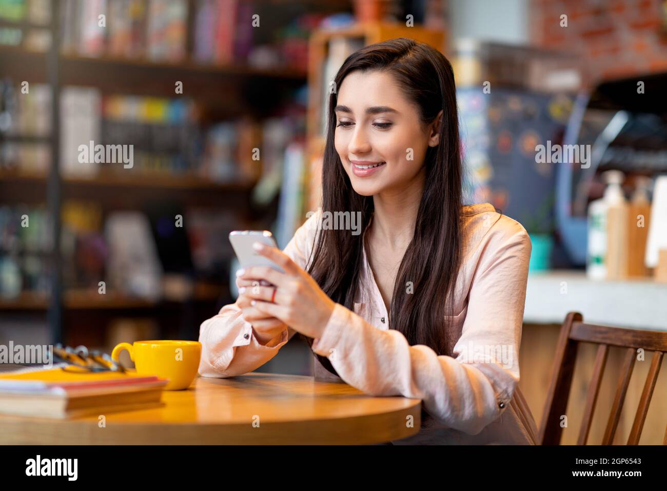 Young happy arab woman using mobile phone, sitting in city cafe and ...