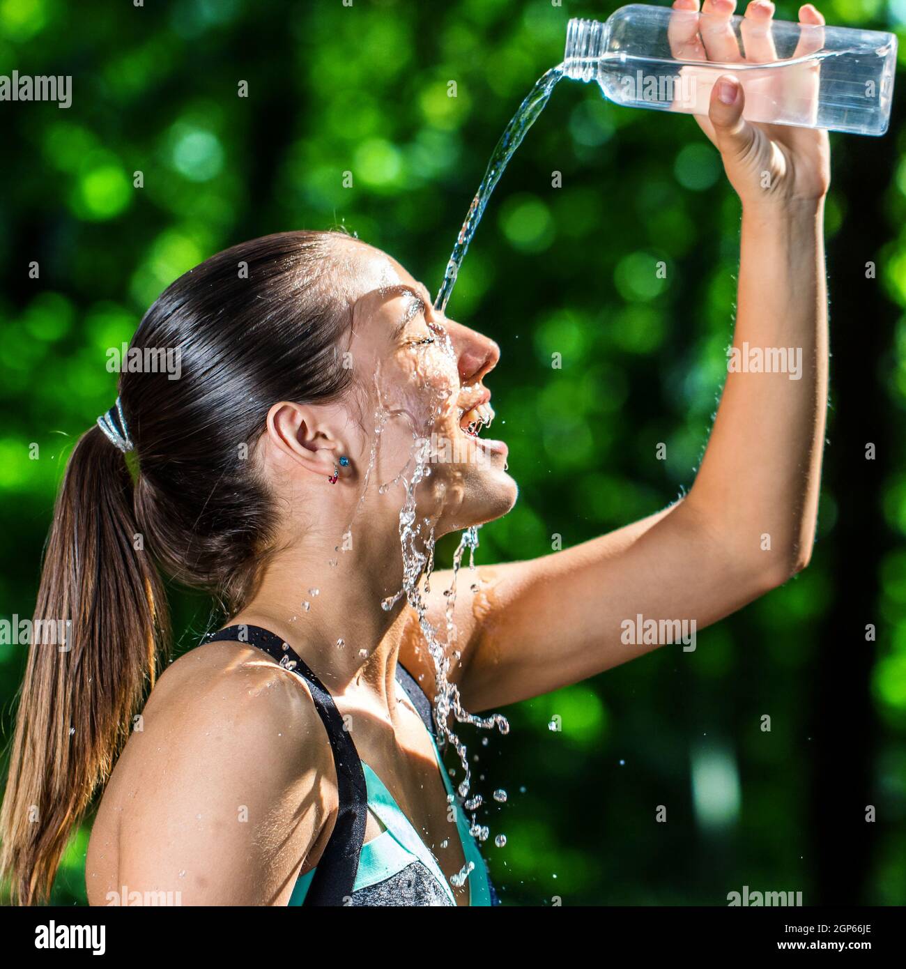 Close up face shot of young fitness girl pouring cold water on face ...