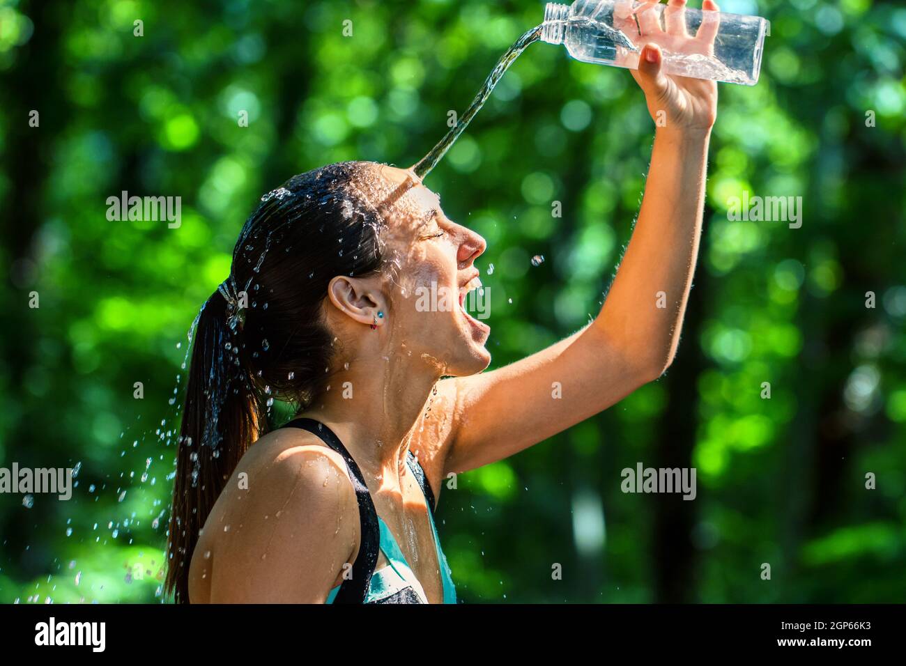 Close up face shot of female runner pouring water on face after workout ...