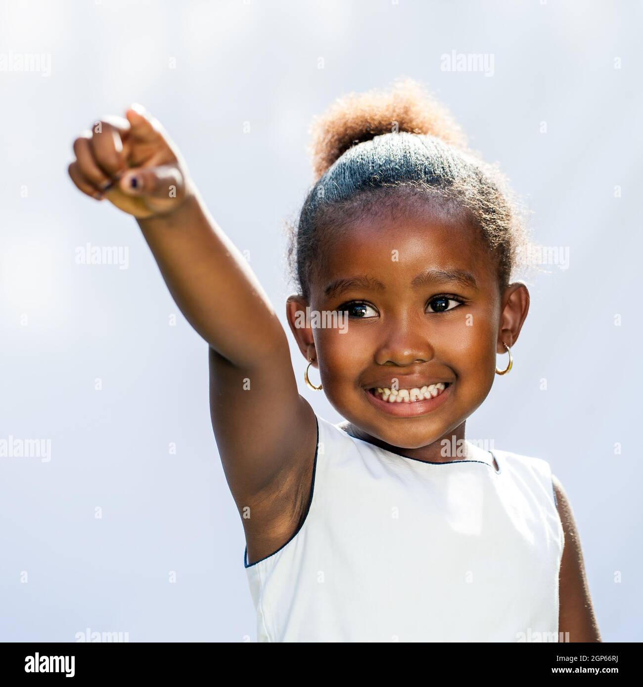 Portrait of small African girl pointing with finger into distance ...