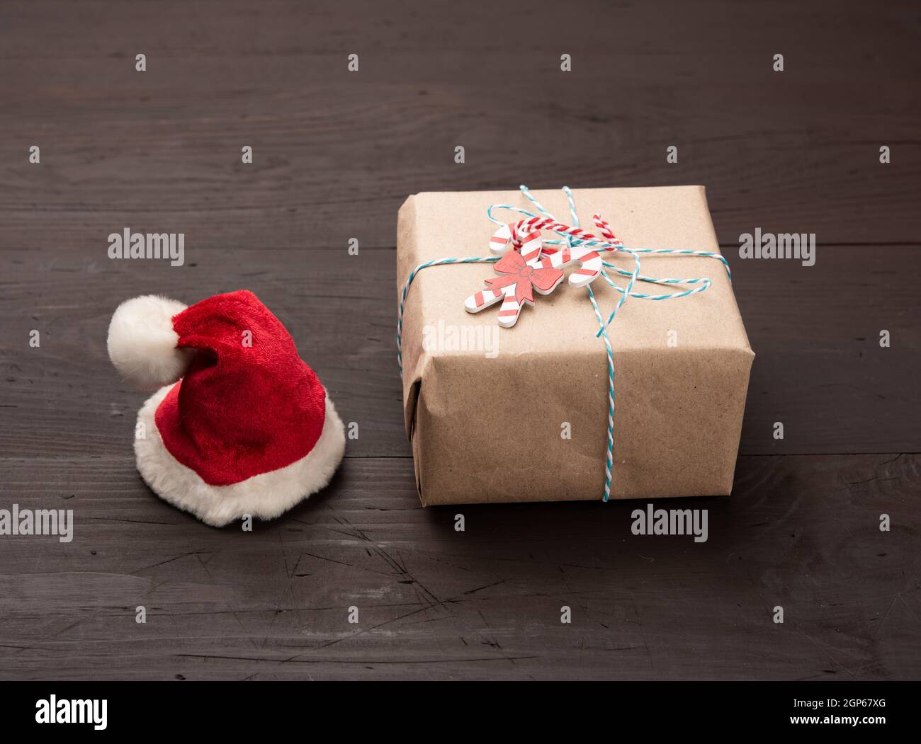 box wrapped in brown kraft paper and red hat, gift on a wooden ...