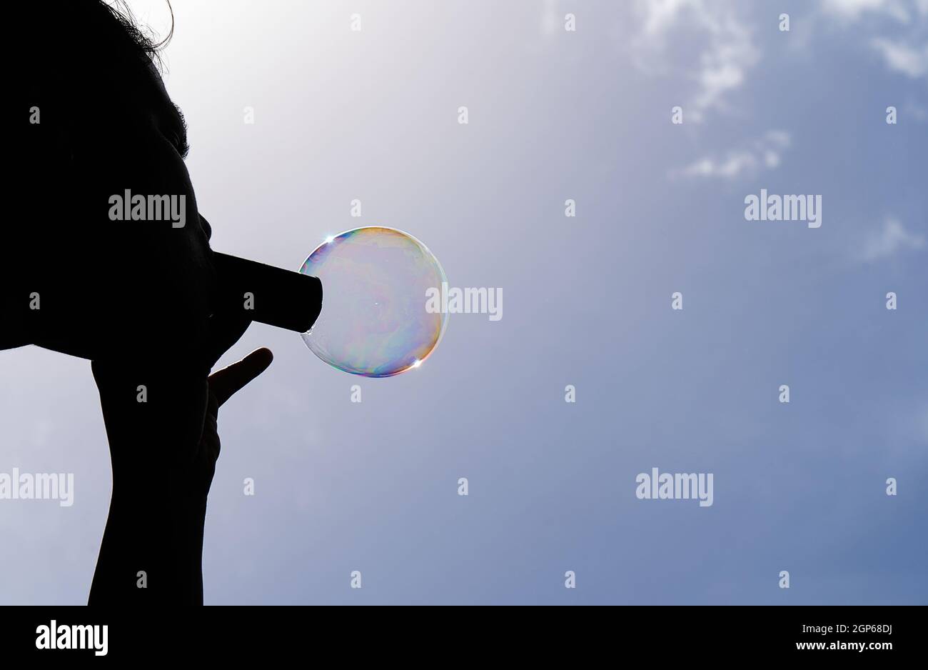Silhouette of a person inflating a bubble and a blue sky in the ...