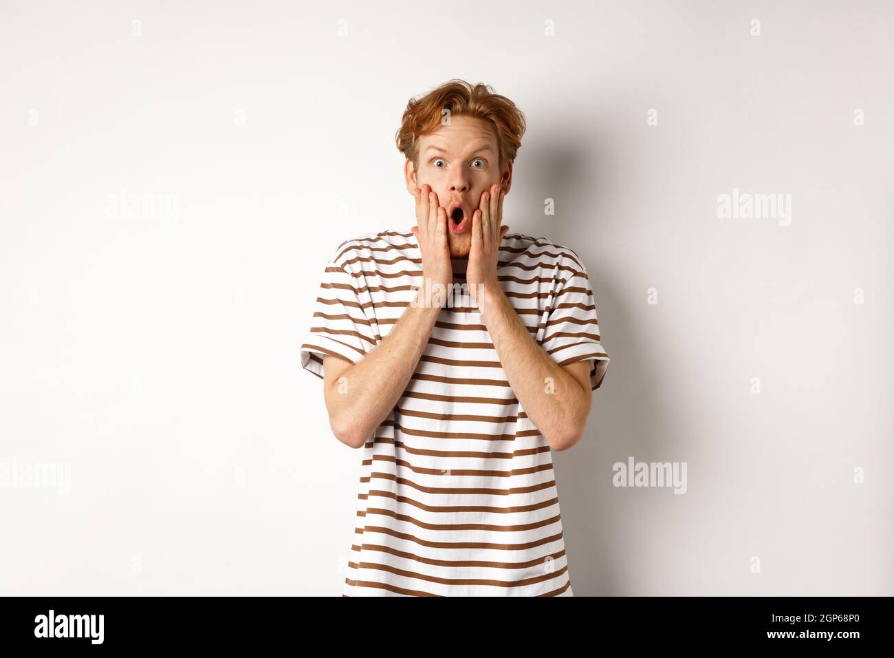 Impressed young man with ginger hair, gasping and staring shocked at ...