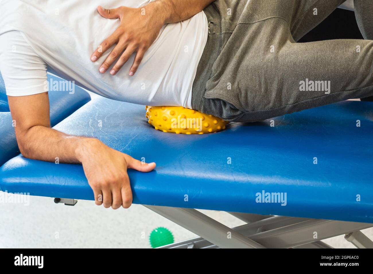 Man using a spiky massage ball to release tight hips. Laying on the ...