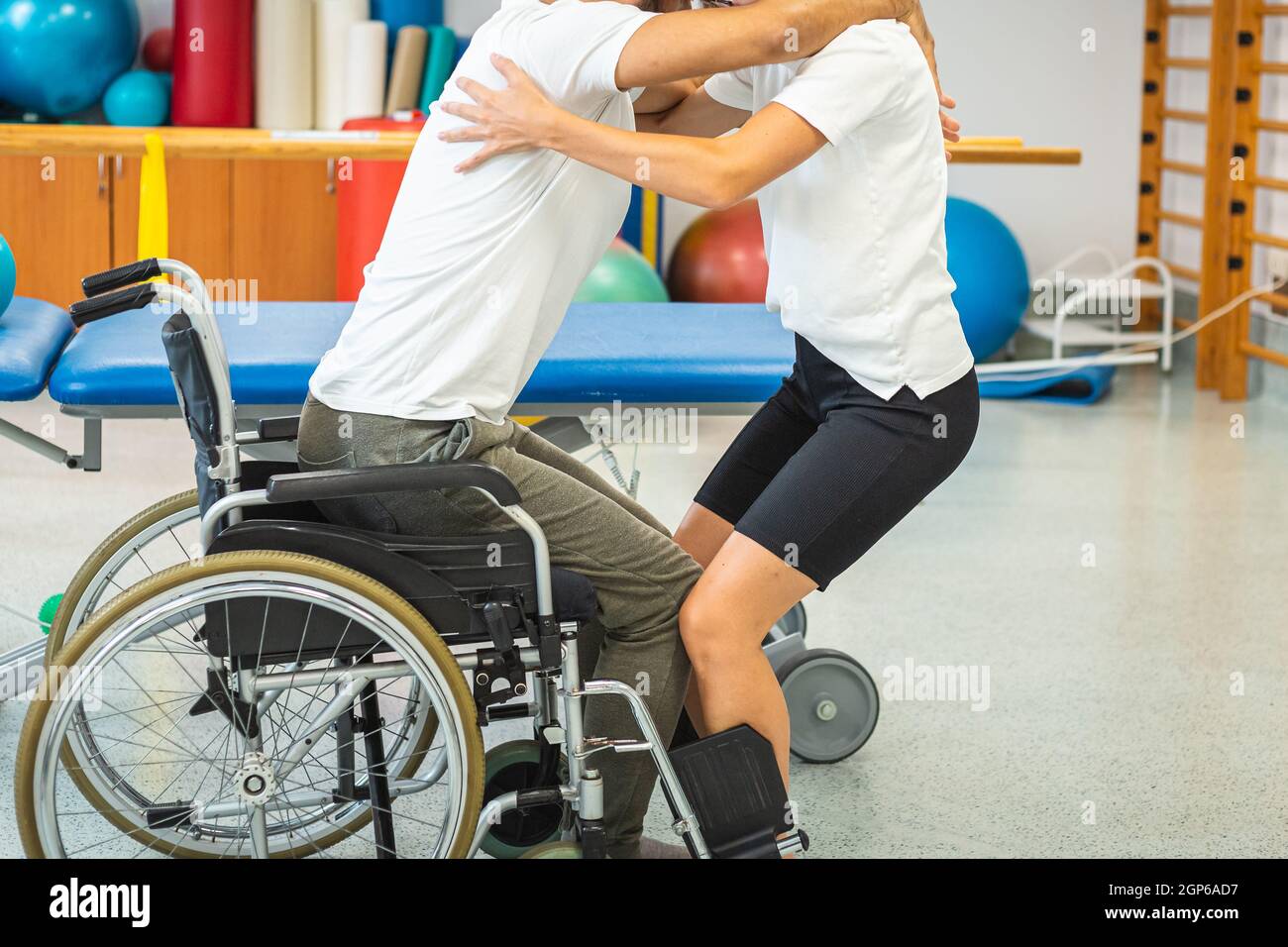 Disabled patient and female physiotherapist, exercise standing up and ...