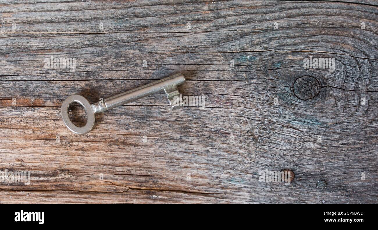 Old key is lying on a rustic wooden desk Stock Photo - Alamy