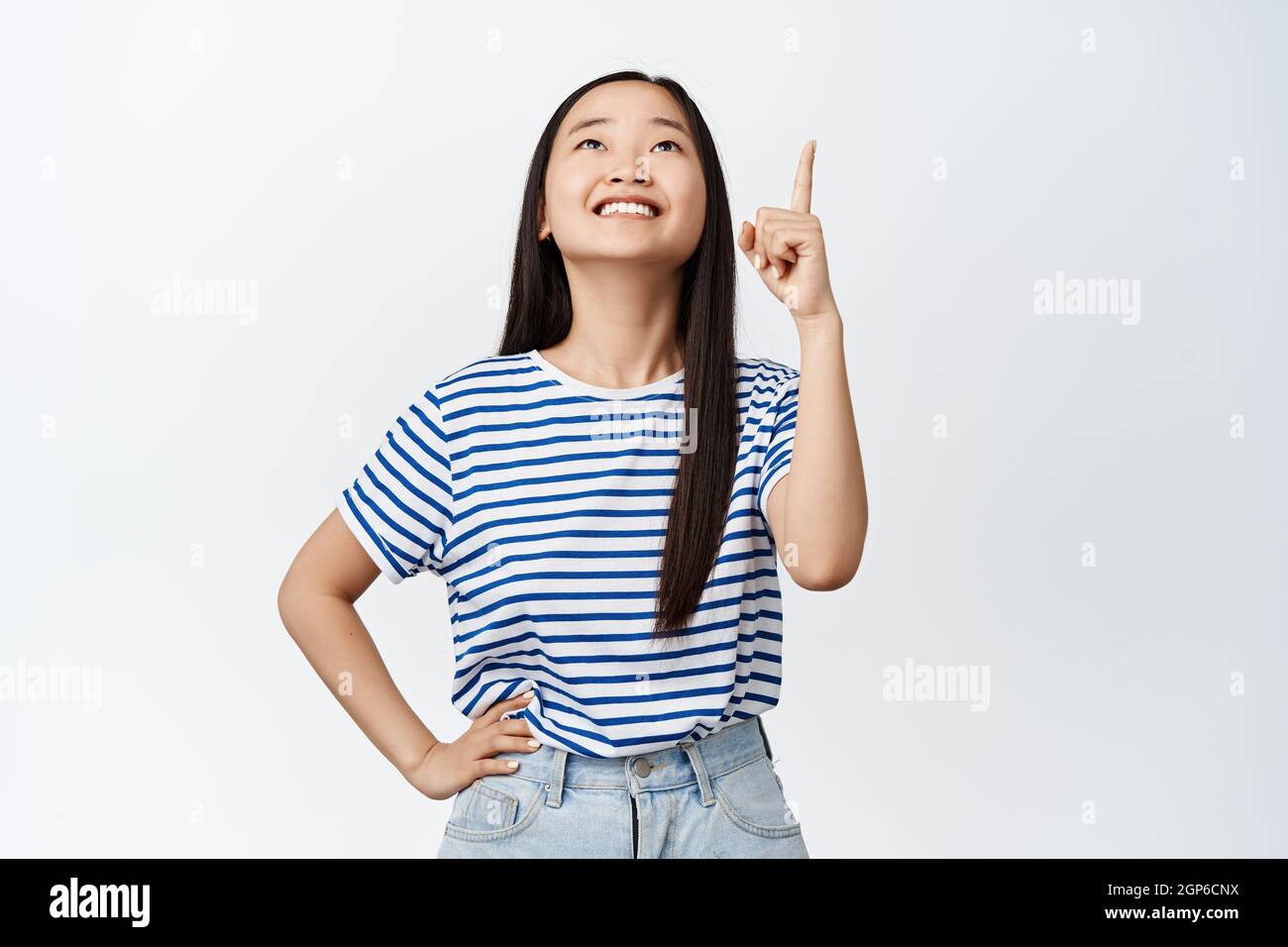 Beautiful asian girl pointing and looking up, smiling with happy ...